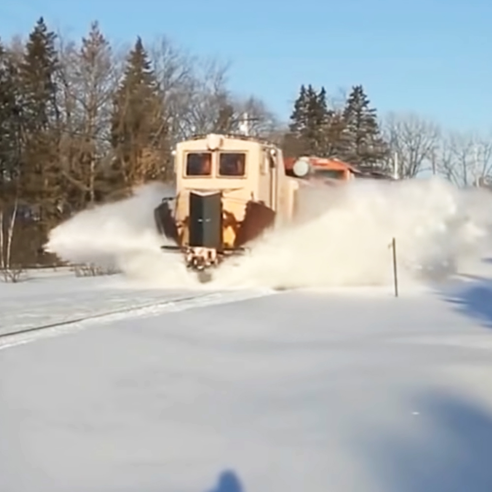 Trains with snow plows turn snow into white tidal waves